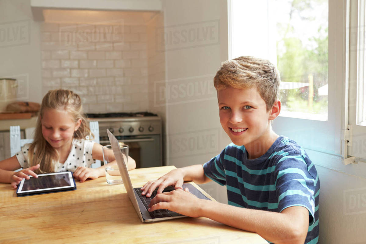 Children At Home Using Digital Devices On Kitchen Table - Royalty-free ...