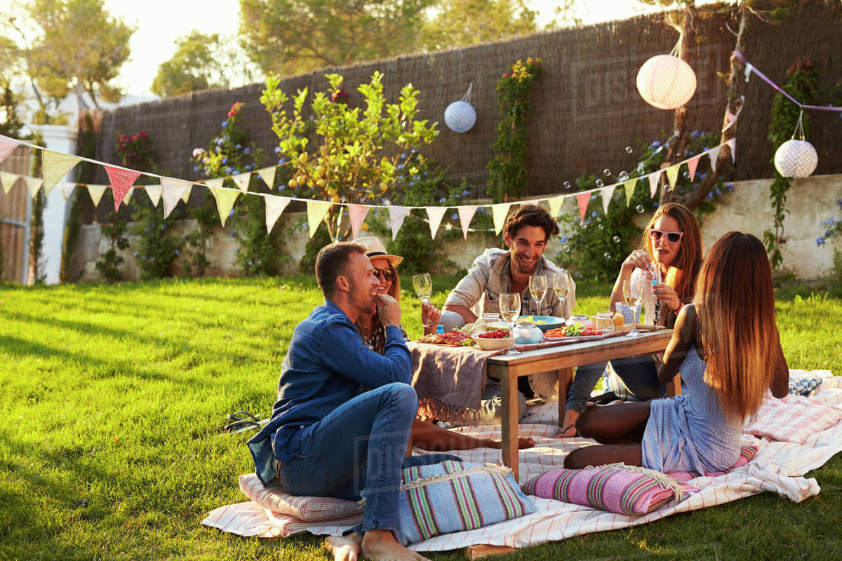 Group Of Friends Enjoying Outdoor Picnic In Garden - Royalty-free Stock ...