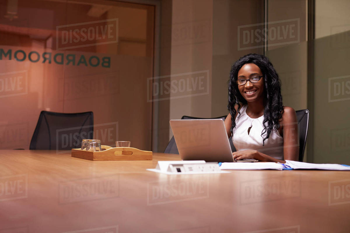 Young black woman working late in office smiling to camera - Royalty ...