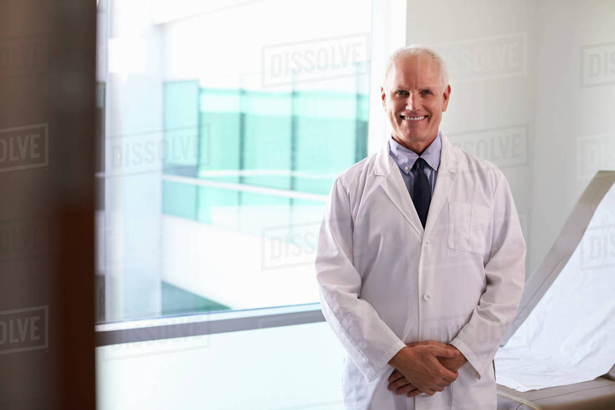 Portrait of male doctor standing in exam room - Royalty-free Stock ...