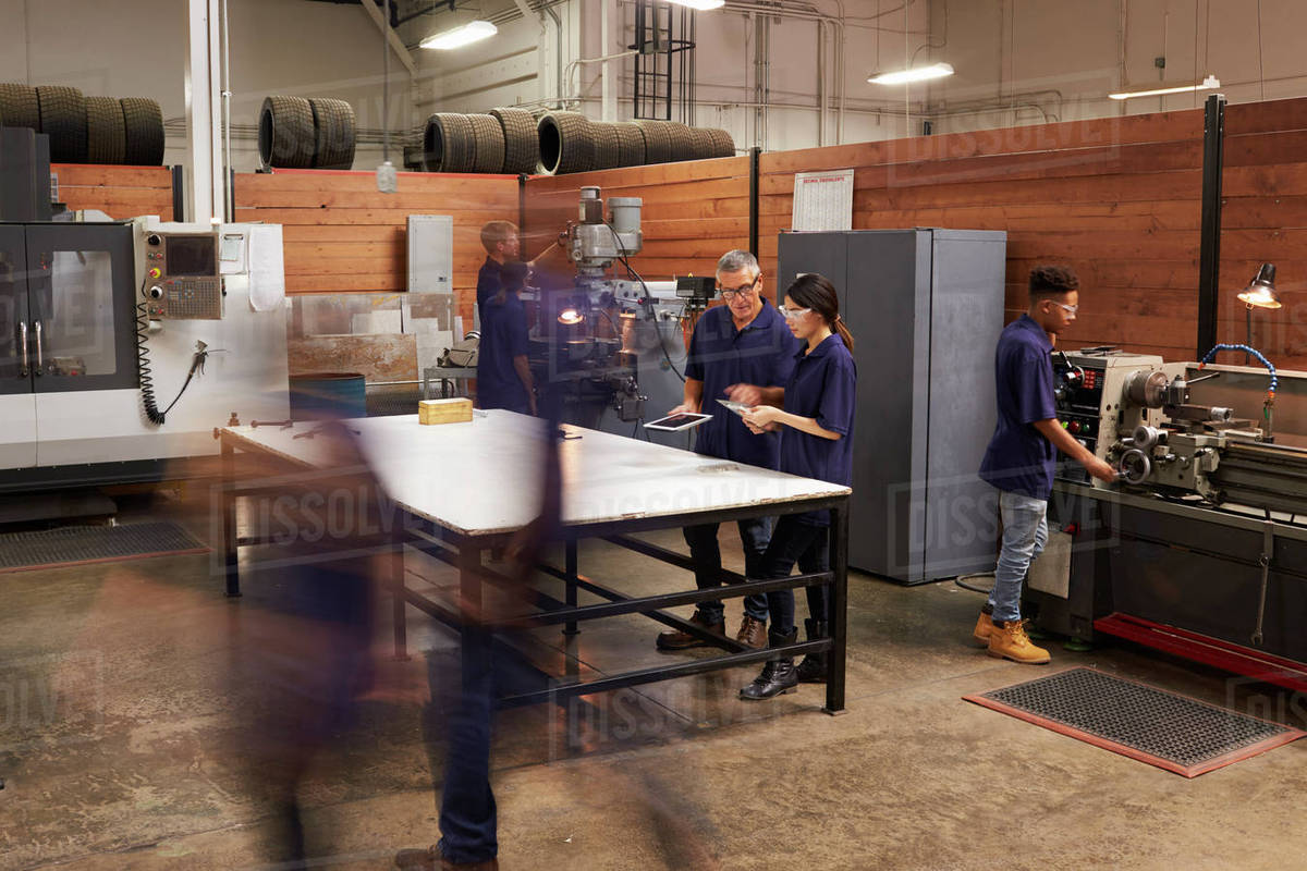 Engineers working on machines in busy metal workshop - Stock Photo ...