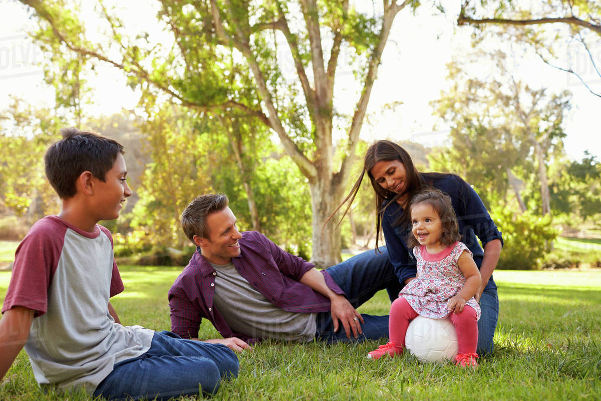 Young mixed race family playing with ball in a park - Royalty-free ...