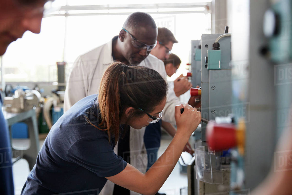 Engineer training female apprentice using a drill press - Royalty-free ...