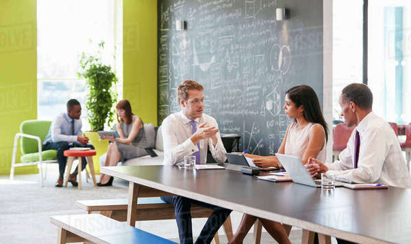 Colleagues talking at work in an informal meeting area - Royalty-free ...