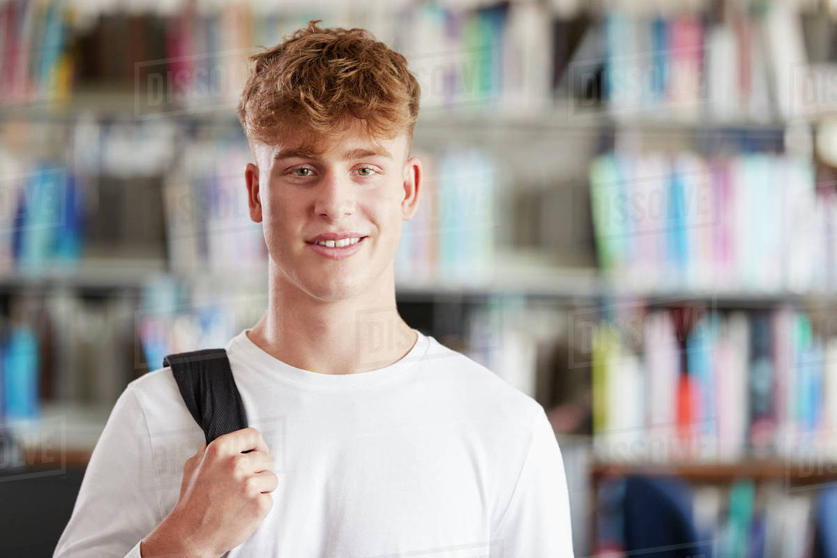 Portrait Of Male Student Standing In College Library - Royalty-free ...