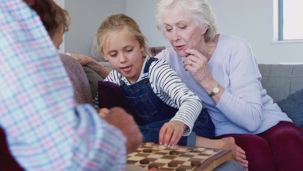 Grandparents Playing Board Game Of Draughts With Grandchildren At Home ...