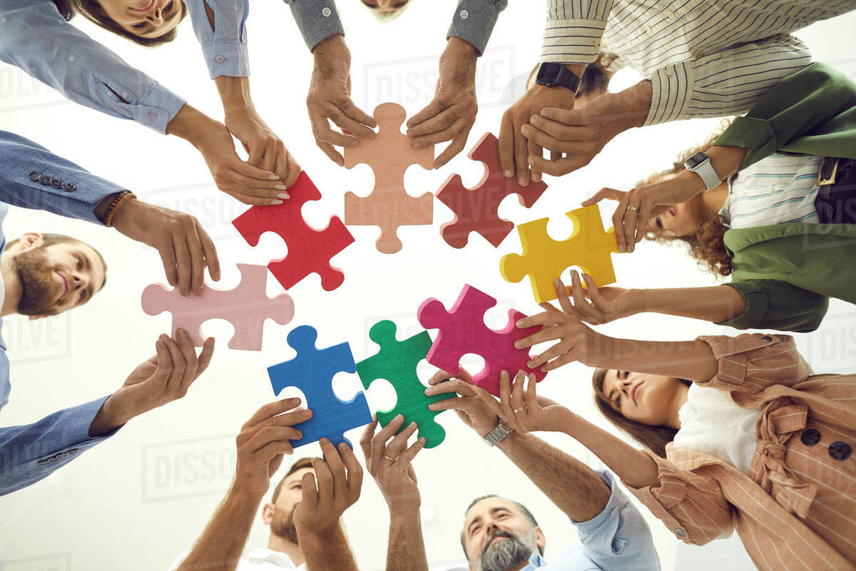Creative business team trying to fit colorful jigsaw puzzle pieces ...