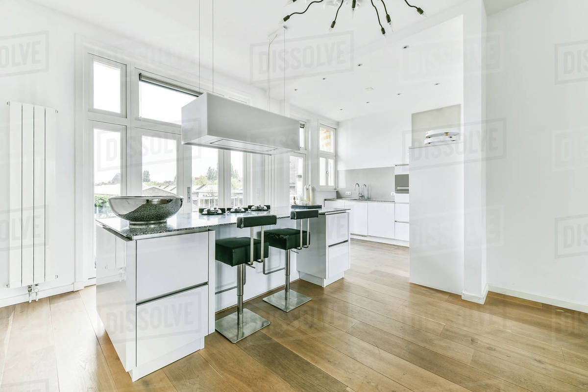 Contemporary counters and stools located under stylish exhaust hood in ...