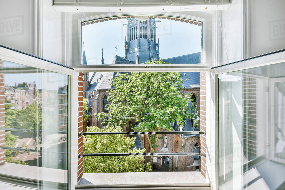 Through opened window of house view of historic building and trees on ...
