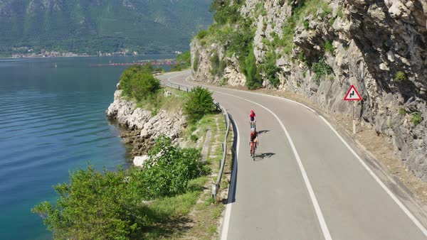 Two cyclists on the sea coast road, aerial view. Fly over cyclists ...