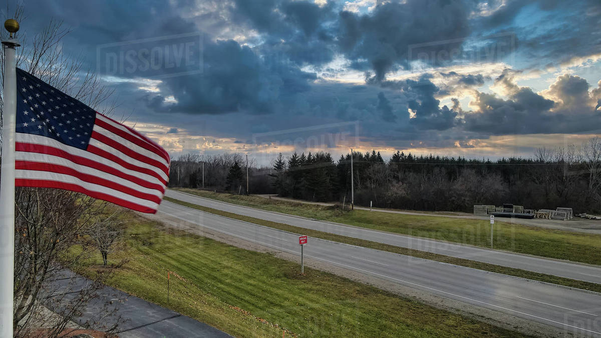 American Flag stands against rural highway under moody sky. - Royalty ...