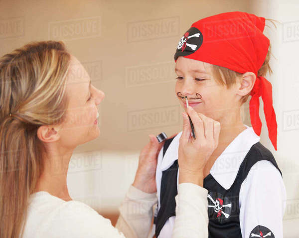 Boy, pirate costume and halloween in home, woman and face paint for ...