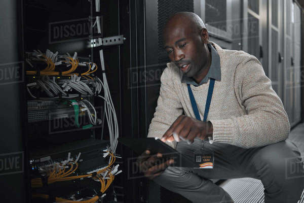 Data center or black man on tablet in server room on database ...