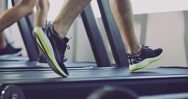 People running on a treadmill equipment together as a group at indoor ...