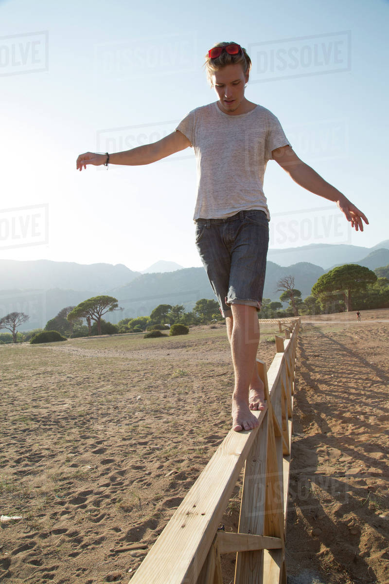 Man balancing on a wooden fence - Royalty-free Stock Photo | Dissolve