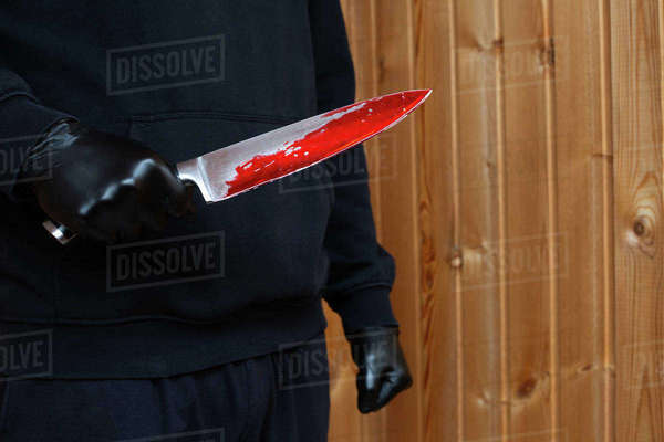 Maniac holds bloody murder weapon in his hand, killer in black gloves ...