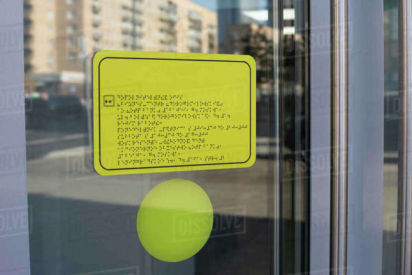 Yellow sign with black writing braille text. The sign is in language ...