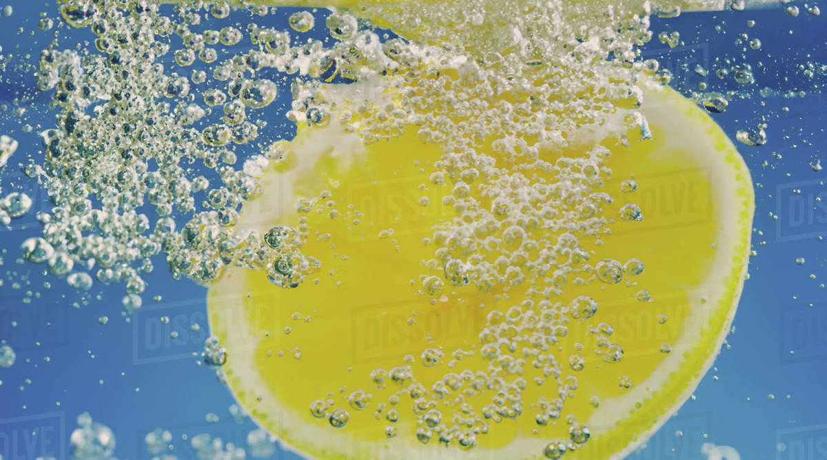 Underwater lemon slice in soda water or lemonade with bubbles. Refreshing soda tonic fizzy ...