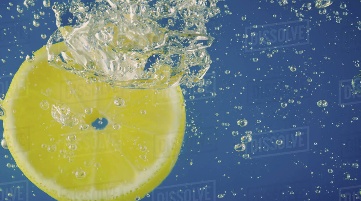 Underwater lemon slice in soda water or lemonade with bubbles. Refreshing soda tonic fizzy ...