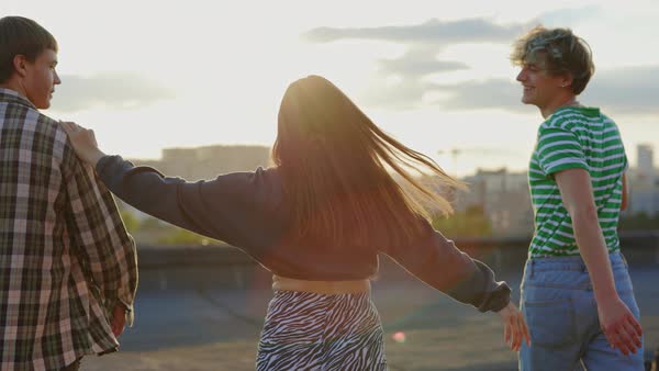 Rooftop party. Back view of the three caucasian friends walking in the ...