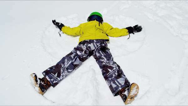 Young boy making a snow angel outdoors on a sunny winter day - 4K ...