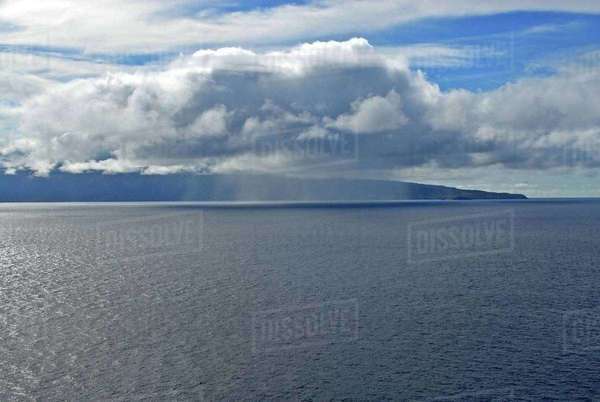 Low rain cloud casting shadow over ocean between islands near Maui ...