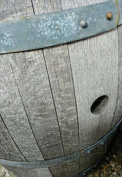Close-up of bung hole in old gray wood cask between stained metal bands ...