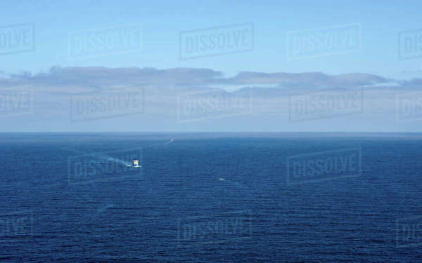 Expansive deep blue ocean seascape with three boats in distance, under ...