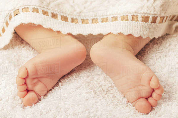 Cute feet of sleeping newborn baby in light bedroom. Family, mot ...