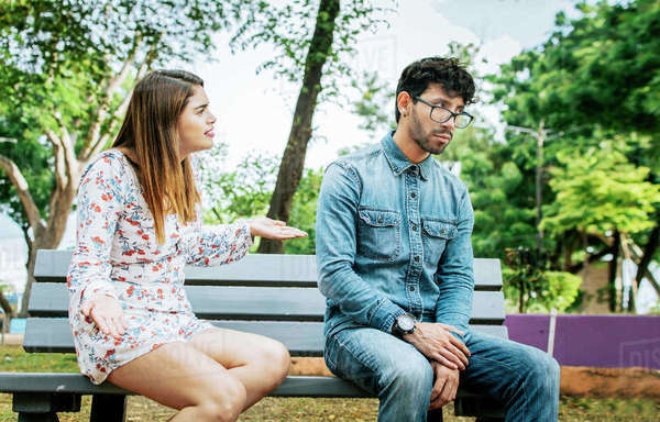 Upset couple arguing in a park. Girl arguing with her boyfriend sitting ...