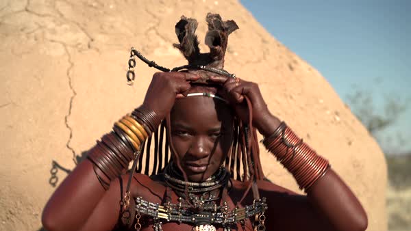 A married Himba woman puts on her Erembe headpiece in a traditional ...
