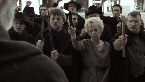 Angry mob dressed in dark clothes wielding tools chants in front of ...