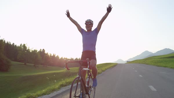 Professional biker raising his arms victoriously after winning race ...