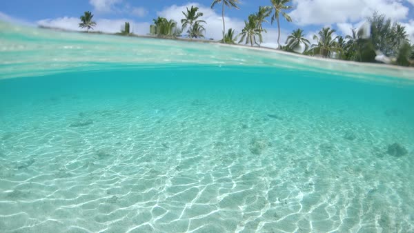 HALF UNDERWATER: Beautiful glassy ocean waves wash the sandy beach near ...