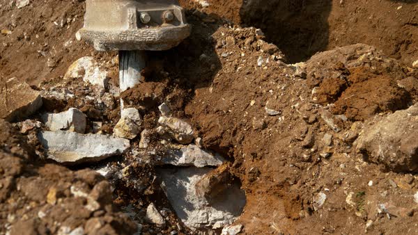 SLOW MOTION, CLOSE UP: Heavyweight jackhammer crushing rocks and moving ...