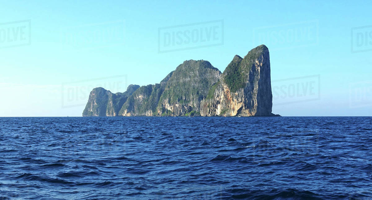 Enormous cliff weathering hot sun and deep blue ocean waves in complete ...
