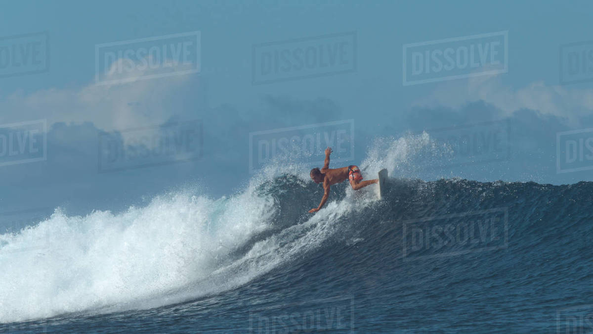 Athletic man on summer holiday does a sharp turn on big wave with his ...