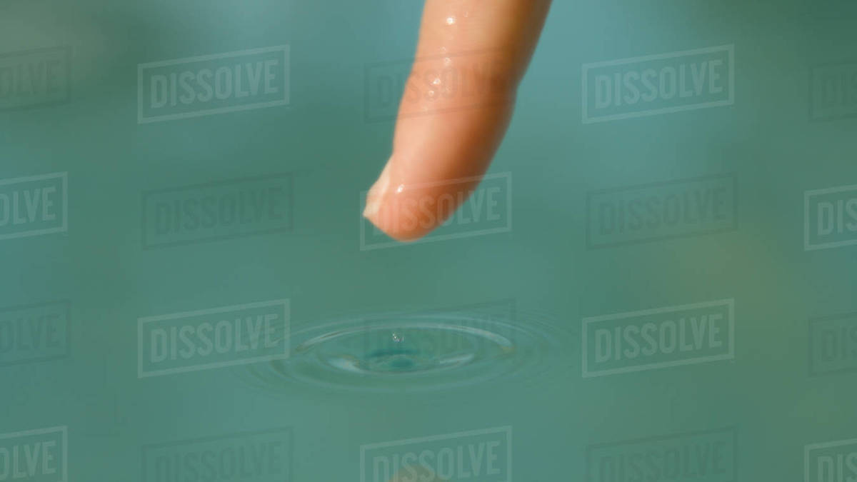 MACRO, DOF: Tiny drop of water falls off finger into large pool and ...