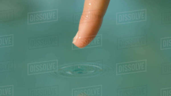 MACRO, DOF: Tiny drop of water falls off finger into large pool and ...