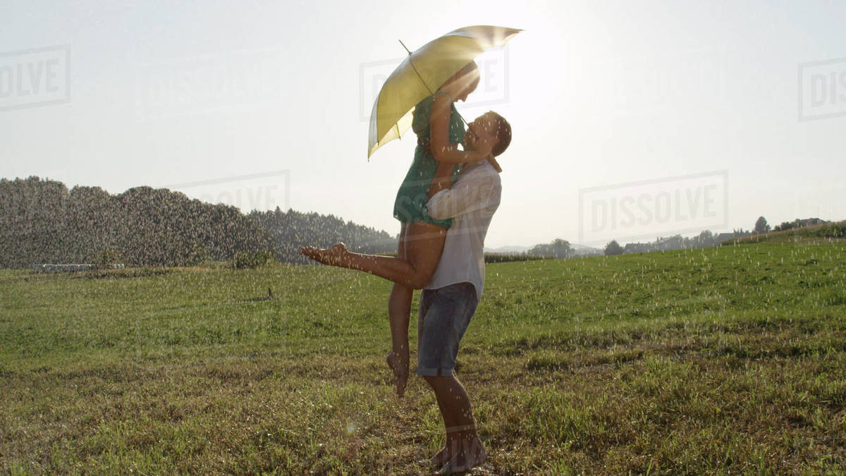 LENS FLARE: Happy young couple dancing in rain on warm romantic day in ...