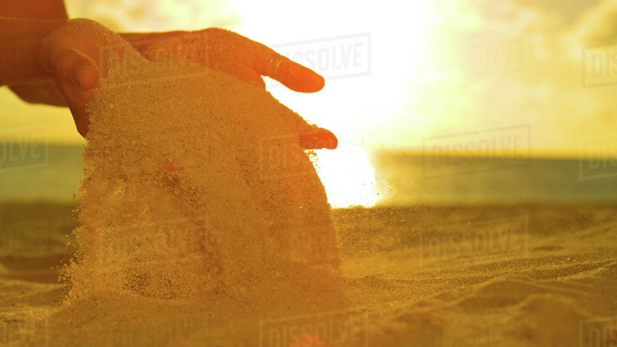 CLOSE UP: Playful woman lifts up a handful of white sand and lets it ...
