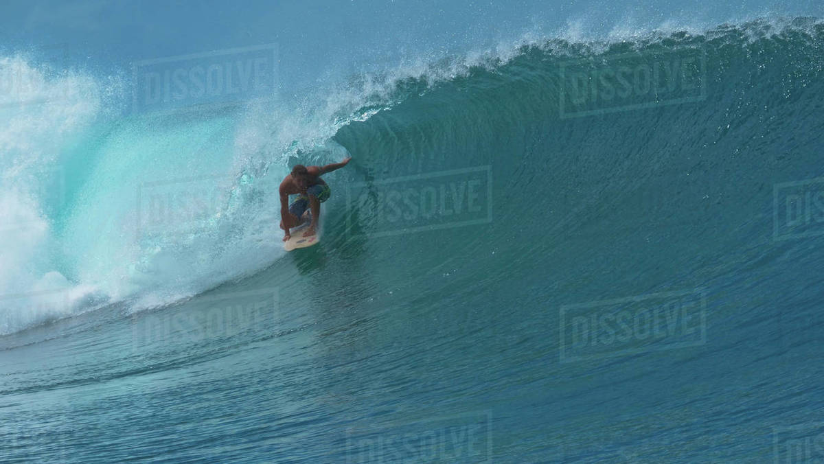 CLOSE UP: Male surfboarder drags his hand behind him through the ...