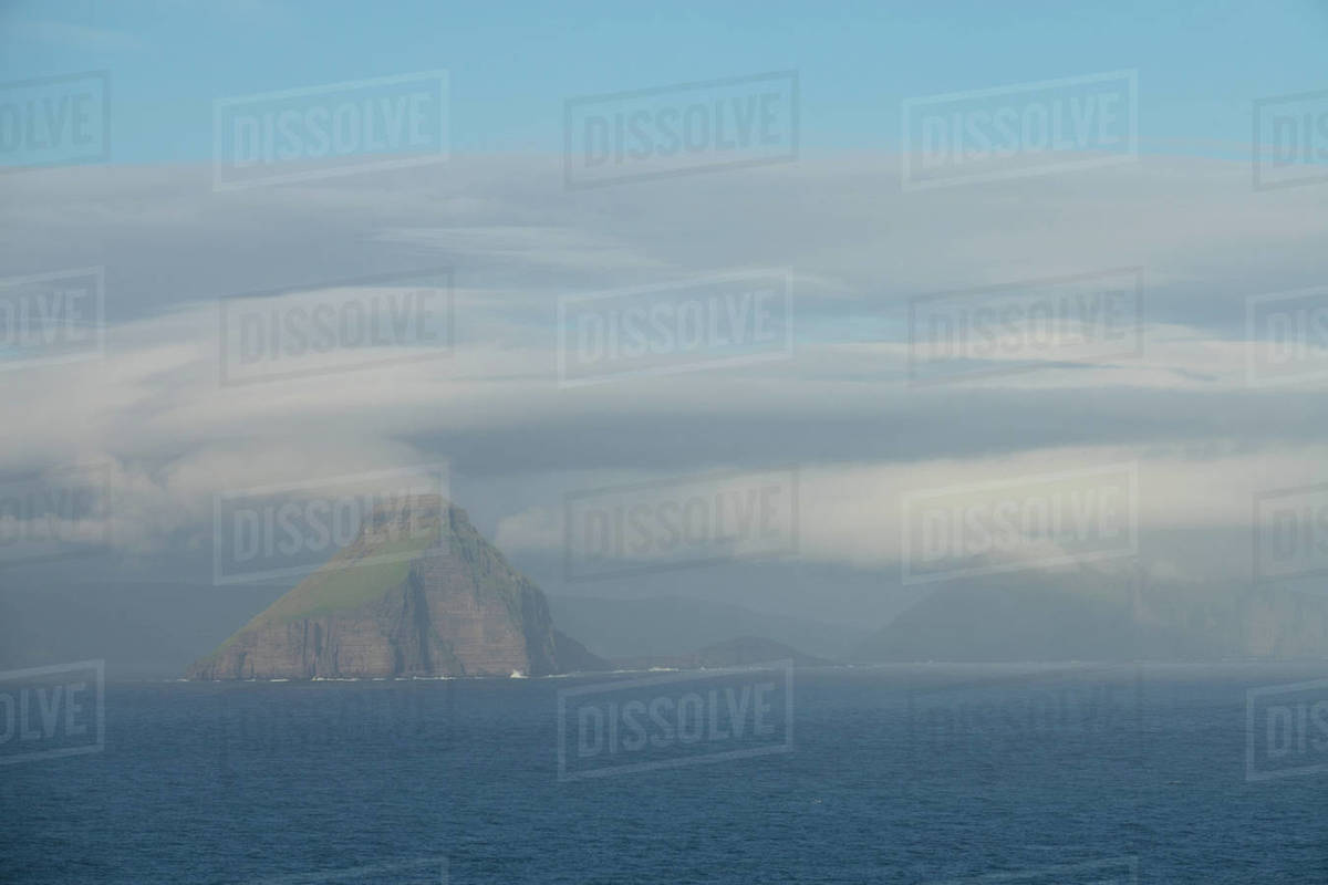 AERIAL: Flying over the ocean and towards the steep mountain in the ...