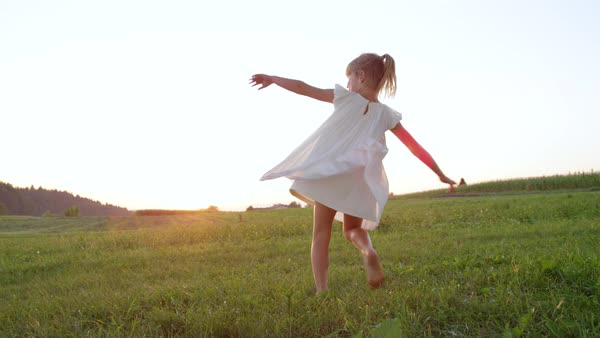 SLOW MOTION CLOSE UP Silly girl dancing and spinning on a green meadow ...