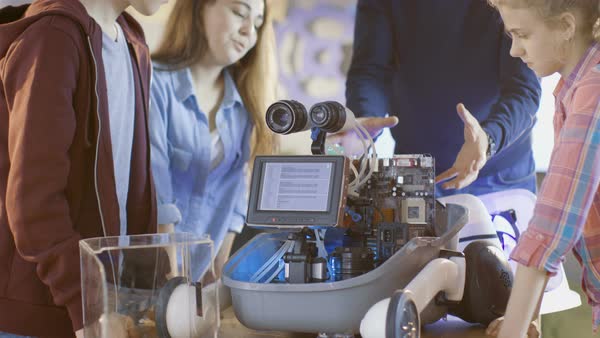 Teacher and his pupils work on a programable robot with led ...