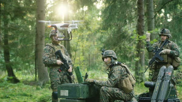 Military staging base, chief army engineer sitting on the boxes of ammunition uses army grade ...