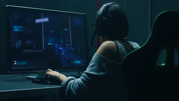 Beautiful professional gamer girl playing in first-person shooter ...