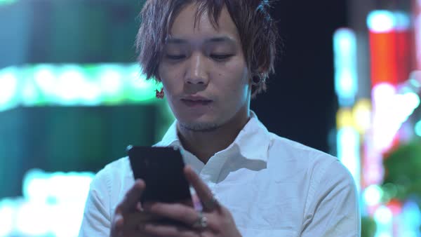 Portrait of the handsome alternative Japanese boy using smartphone. In ...