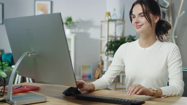 Portrait of the beautiful young woman working on personal computer from ...
