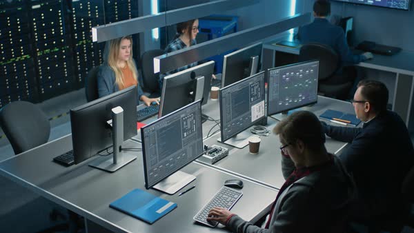 Team of it programers working on desktop computers in data center ...